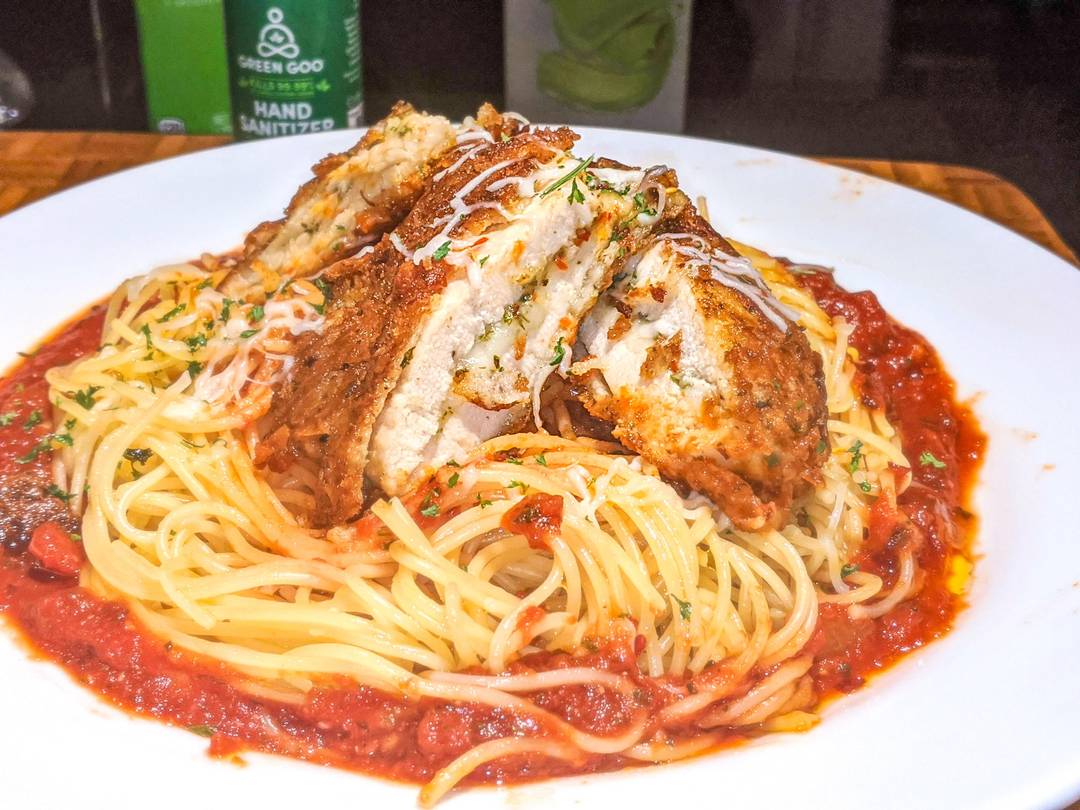 Herb and cheese-stuffed, parmesan crusted chicken parm over a spaghetti pomodoro bed | Scrolller
