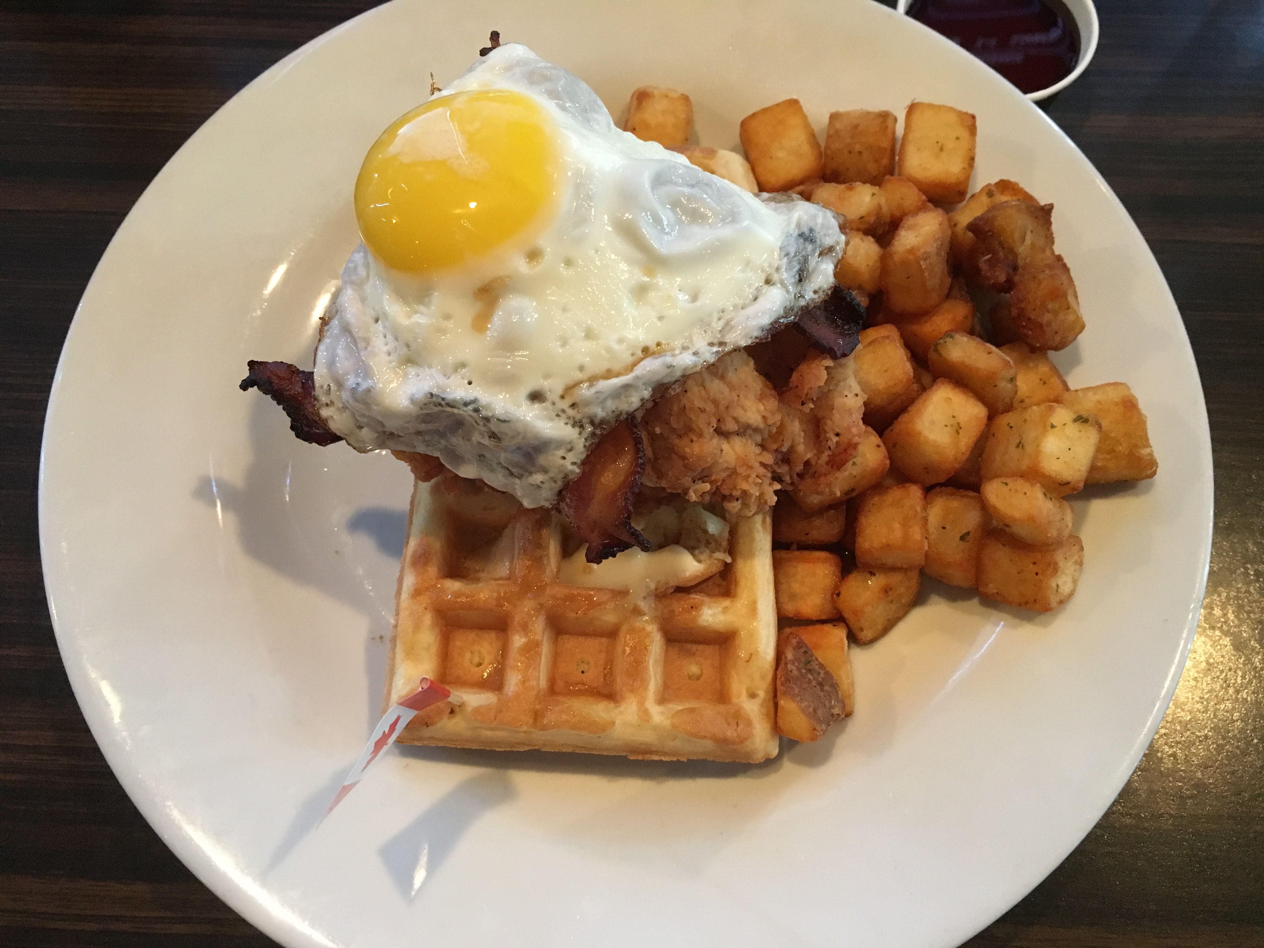 Egg on top of a piece of fried chicken on top of two waffles, hash browns and bacon. Great ...
