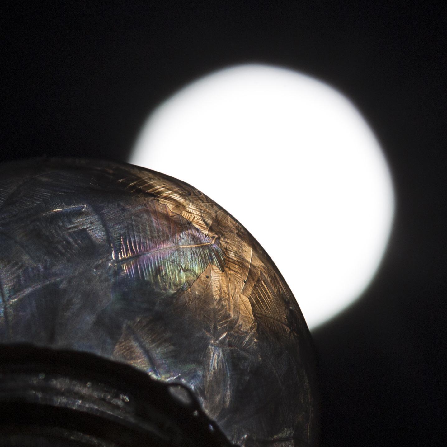 Frozen bubble backlit by full moon. | Scrolller