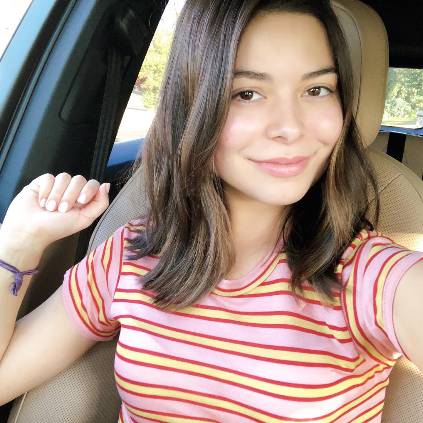 Miranda Cosgrove Sitting In Her Car On A Parking Lot And Giving