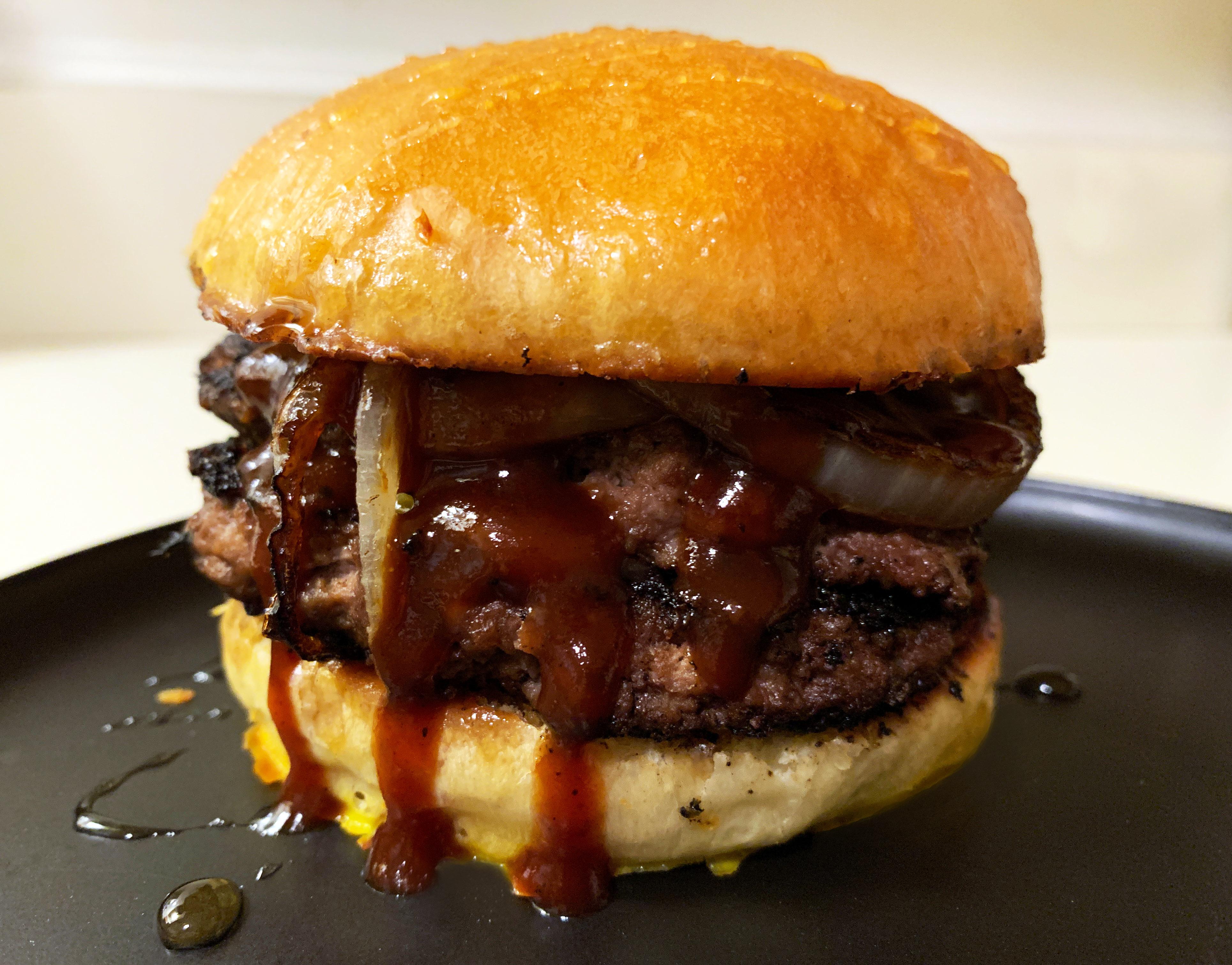 Smash burger on homemade brioche bun drizzled w/ honey, w/ sautéed onions and barbecue sauce ...