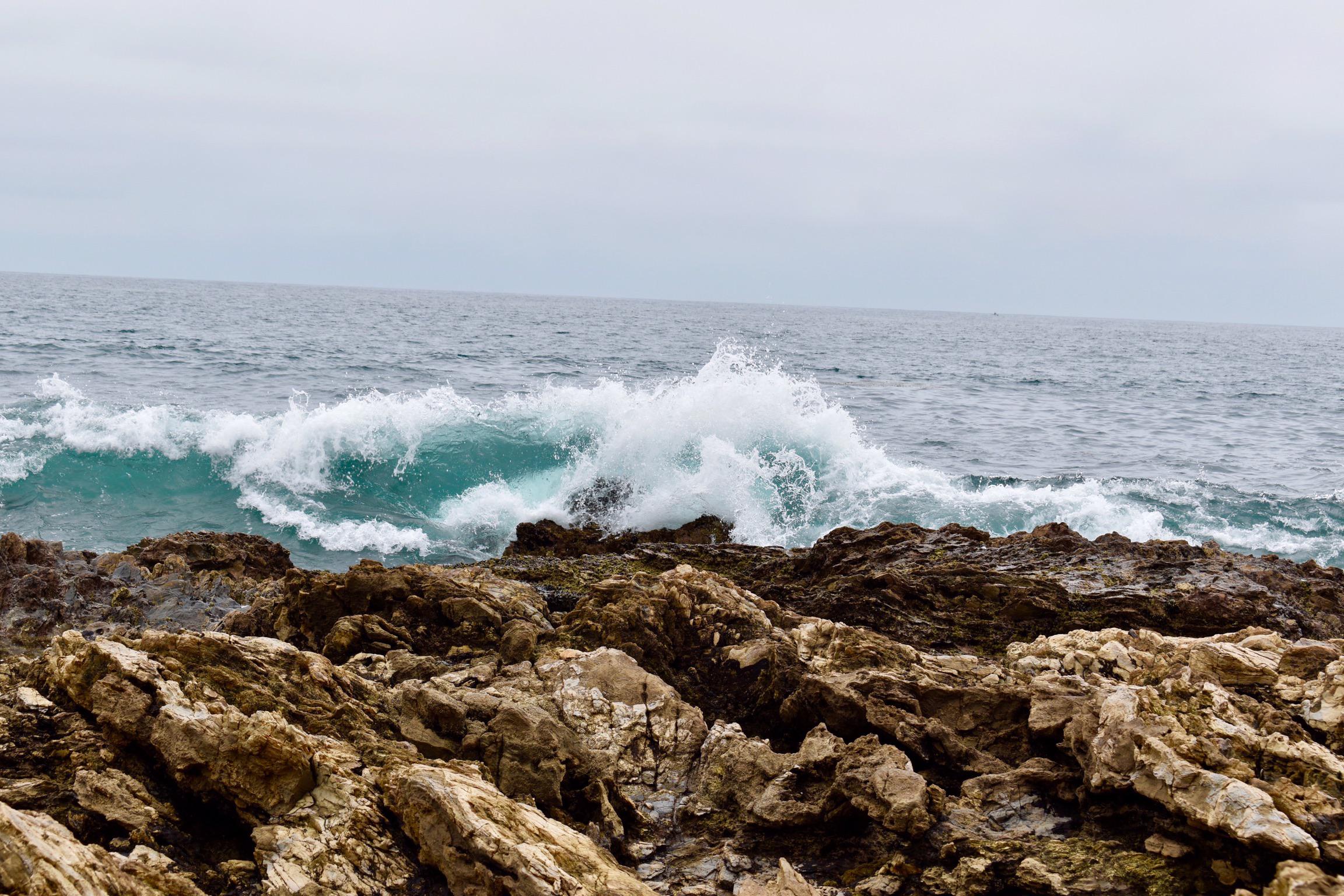 Wave hitting rock | Scrolller