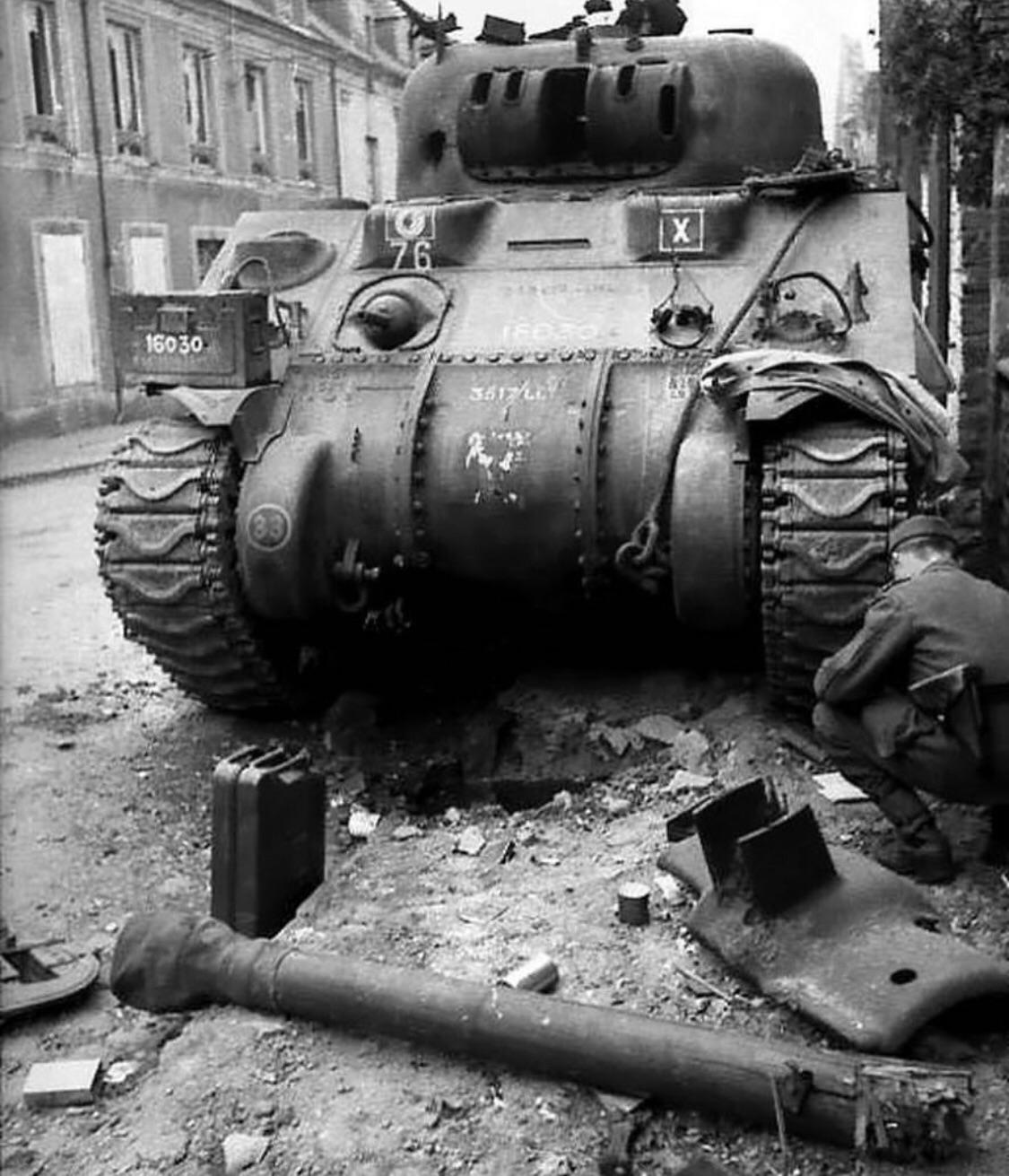 A German soldier inspecting a destroyed American Sherman. | Scrolller