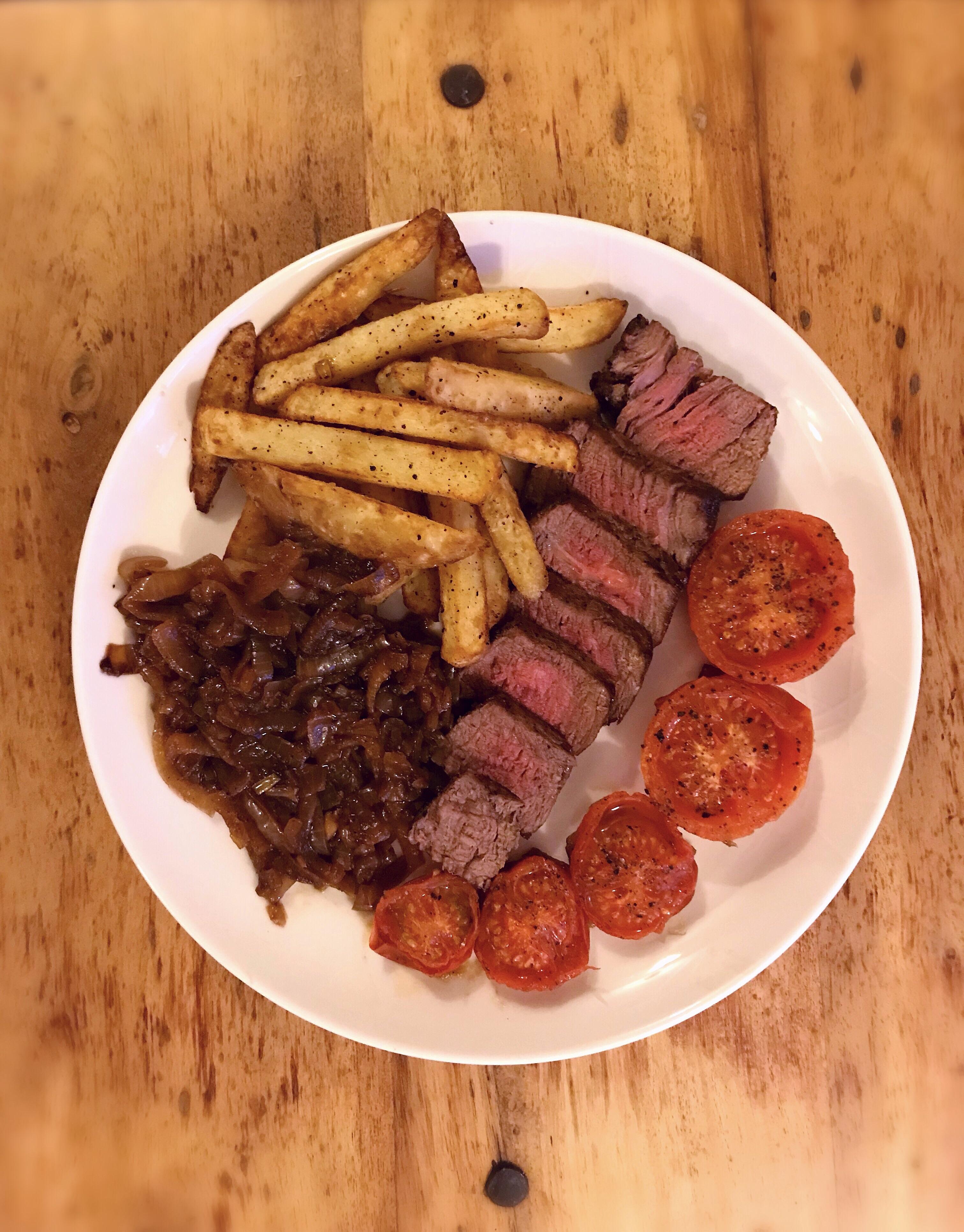 Fillet steak, homemade chips, caramelised onions and roast tomatoes. | Scrolller