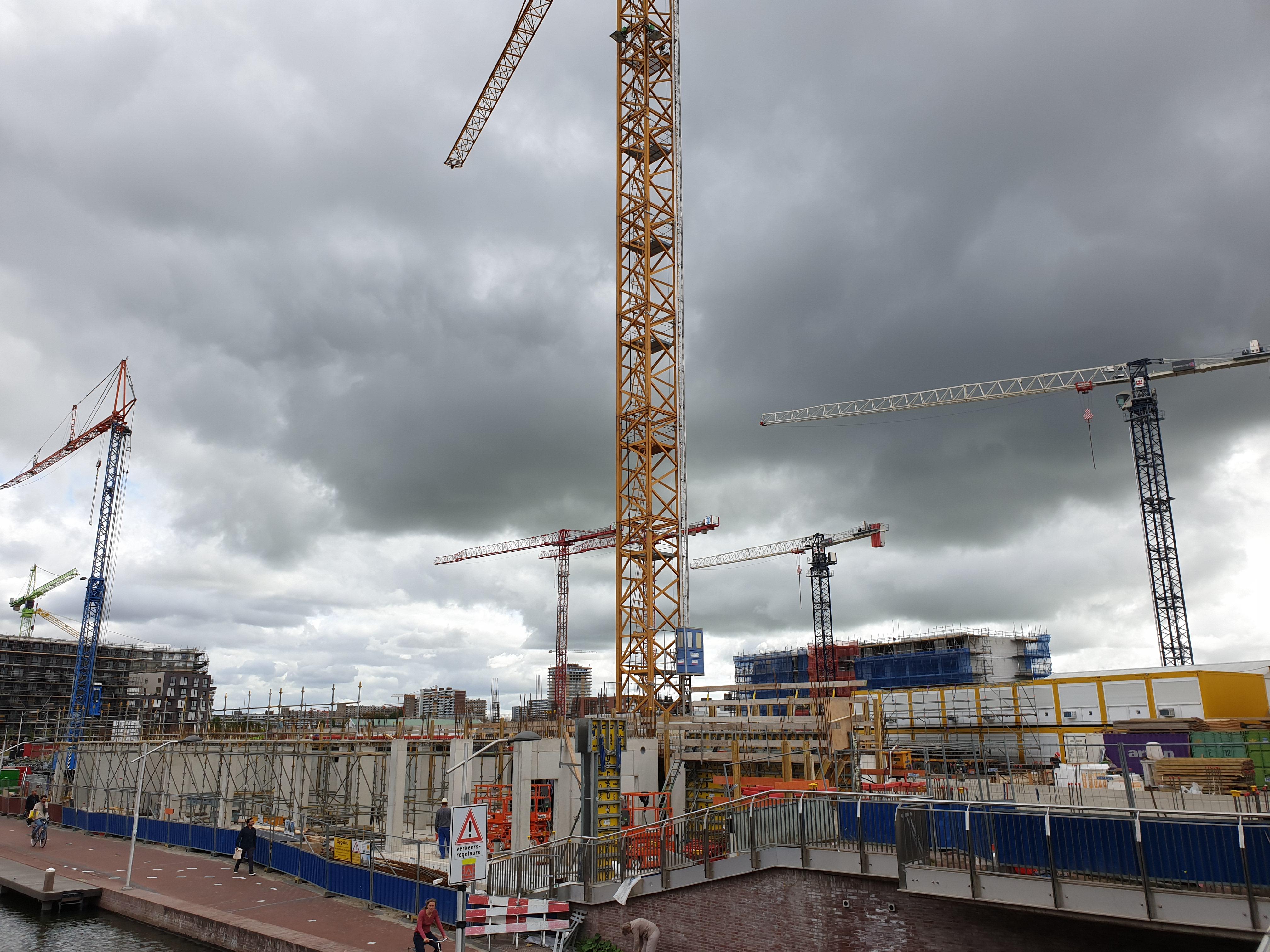 Hoisting cranes surounded by dark clouds | Scrolller
