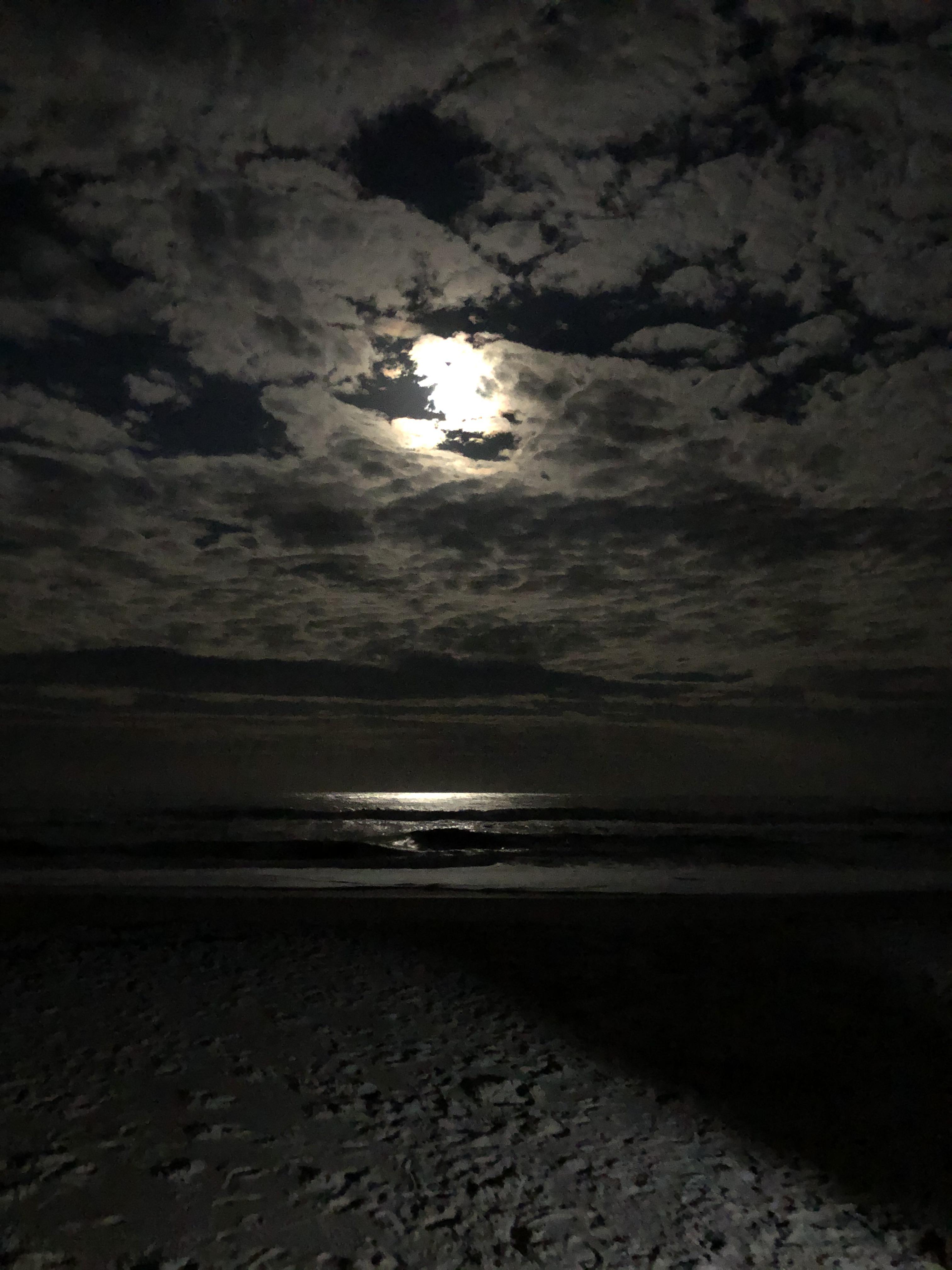 Moon casting light through the clouds n the ocean at Assateague National Park | Scrolller