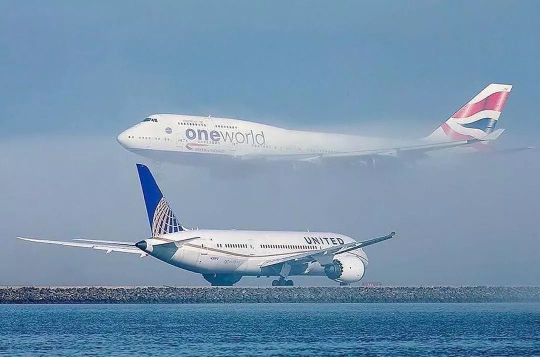 Oneworld (British Airways) Boeing 747-436 comes out of the fog landing over United Airlines 787 ...