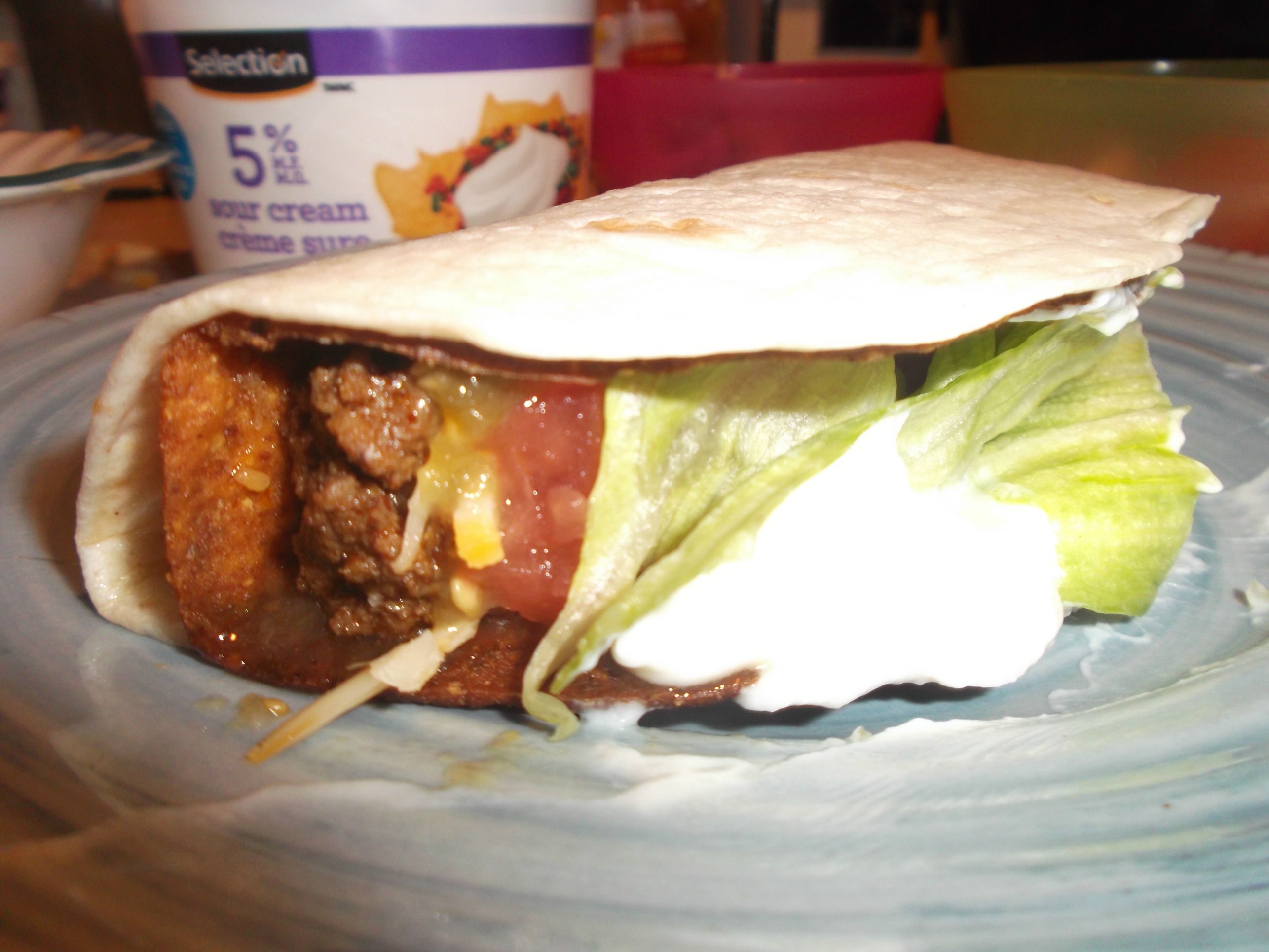 Tacos wrapped in a tortilla around a hard shell with seasoned ground beef, cheese, green salsa ...