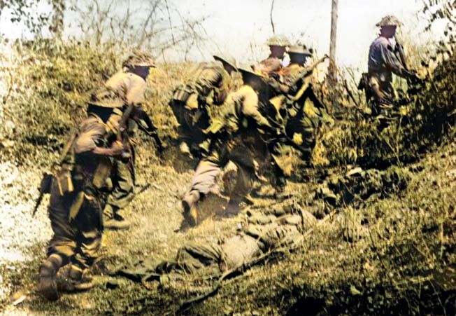 British soldiers move quickly past a dead Japanese soldier in an ...