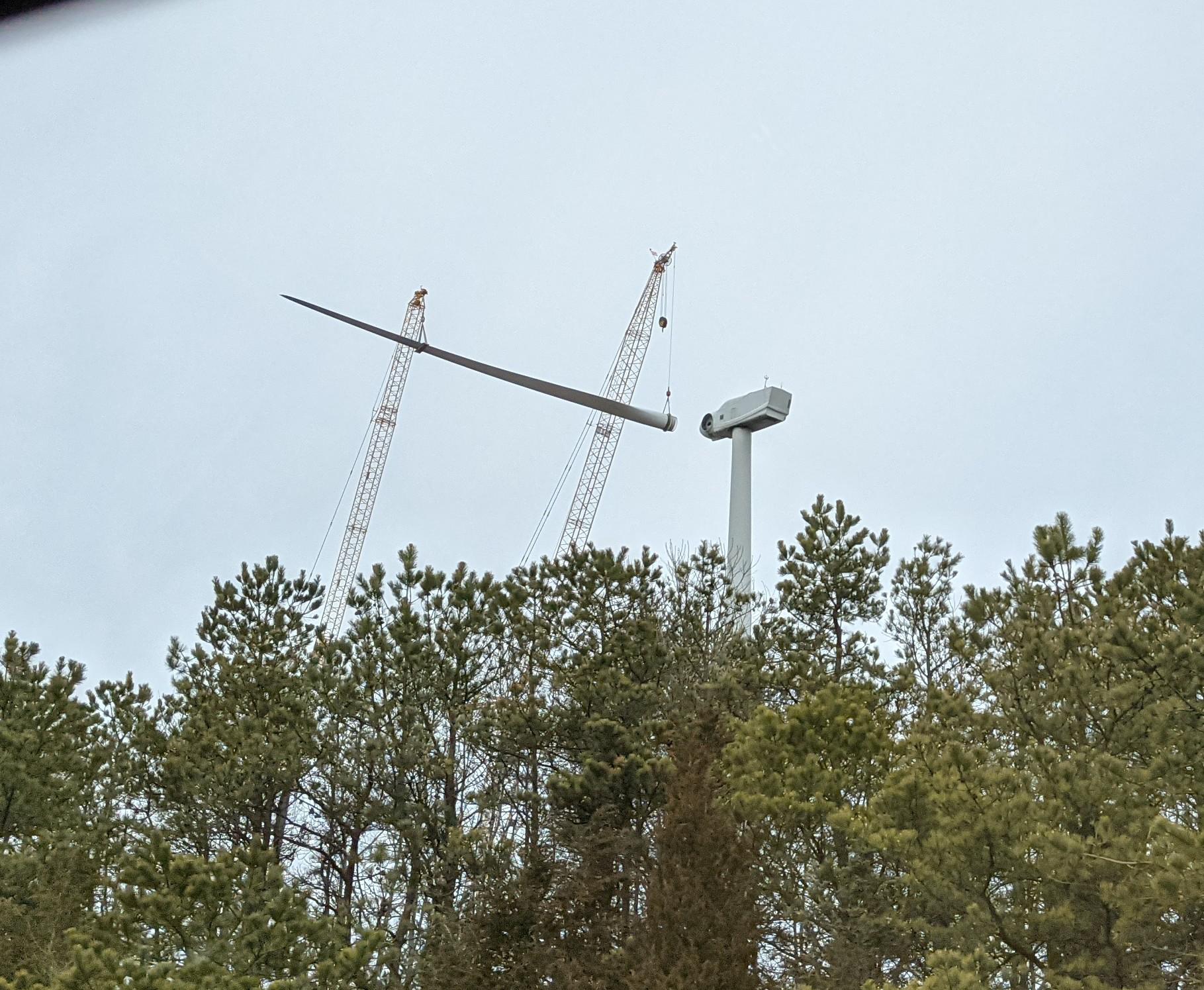 Two cranes replacing blade on a wind turbine. | Scrolller