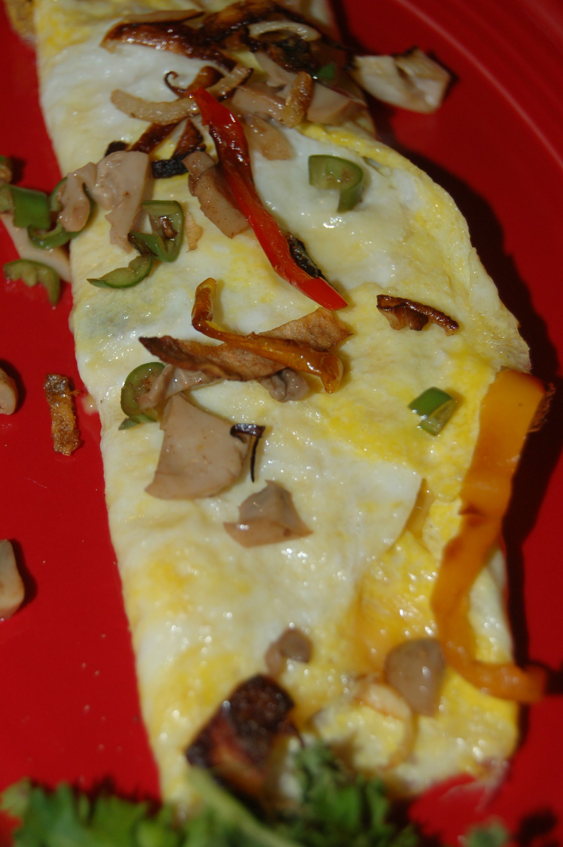 Cheese omelet with red, yellow and orange peppers, onions, serano peppers and mushrooms. | Scrolller
