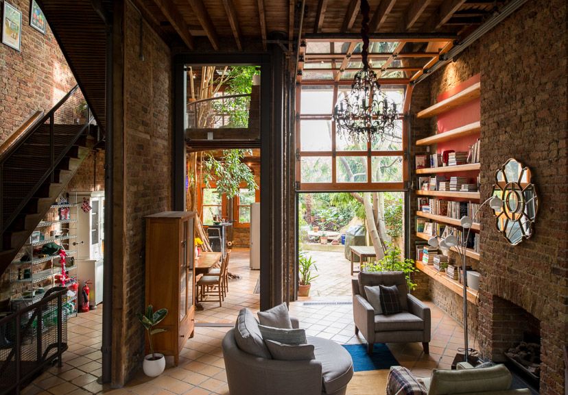 Indoor tree growing in a brick living space with a huge up-and-over door opening up to the ...