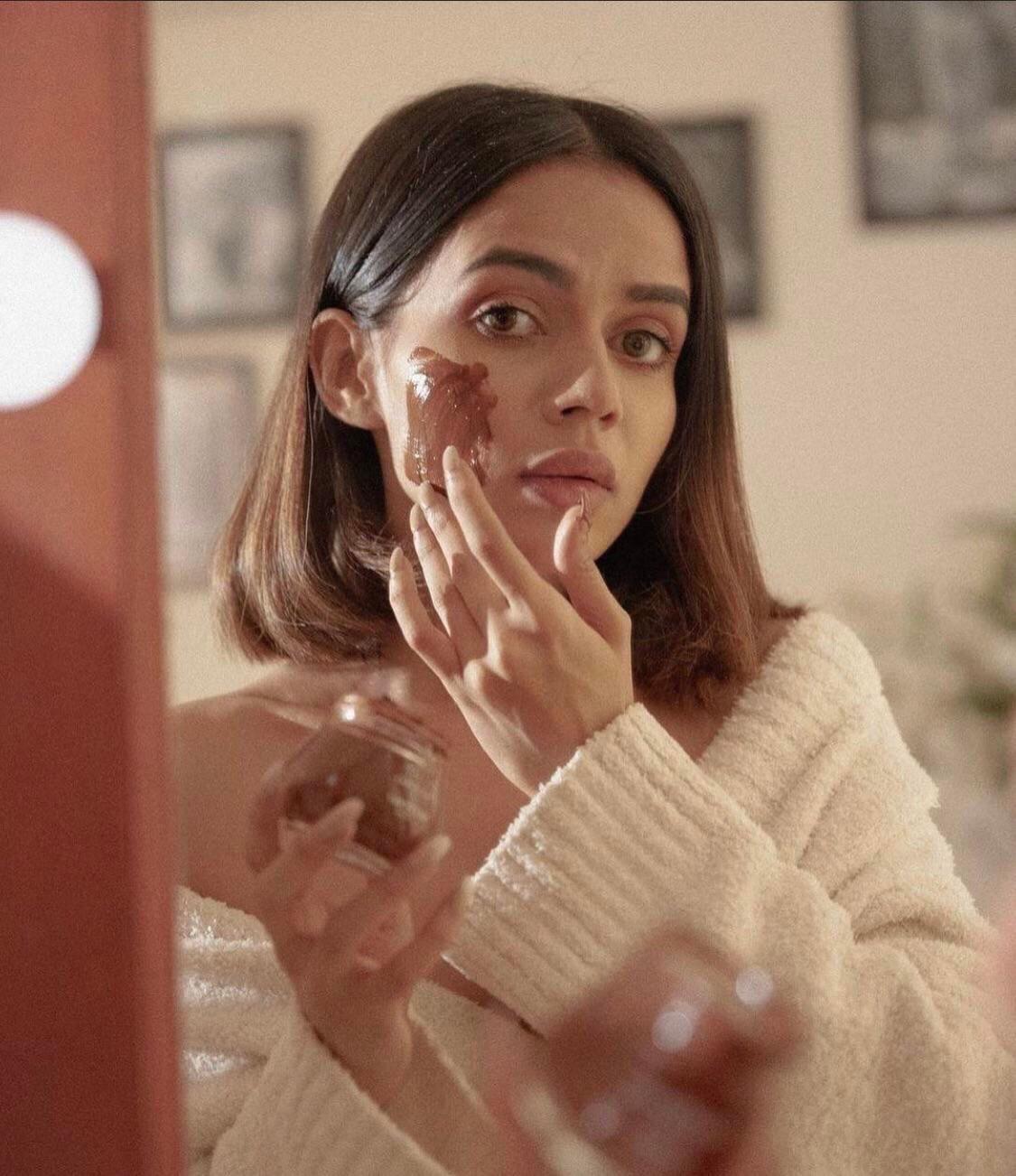 Influencer putting on a face mask with makeup on. A filter to complete ...