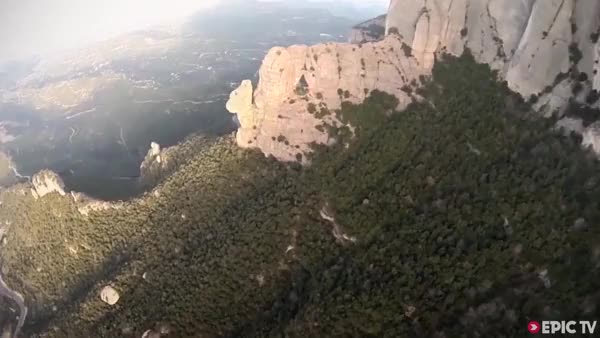 Wingsuit flight through a hole in a cliff | Scrolller