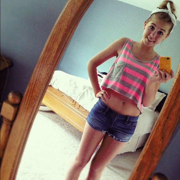 Girl in pink and grey striped crop top baring midriff and belly ring | Scrolller