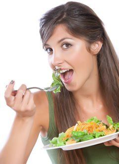 Woman lifting up fork while smiling | Scrolller