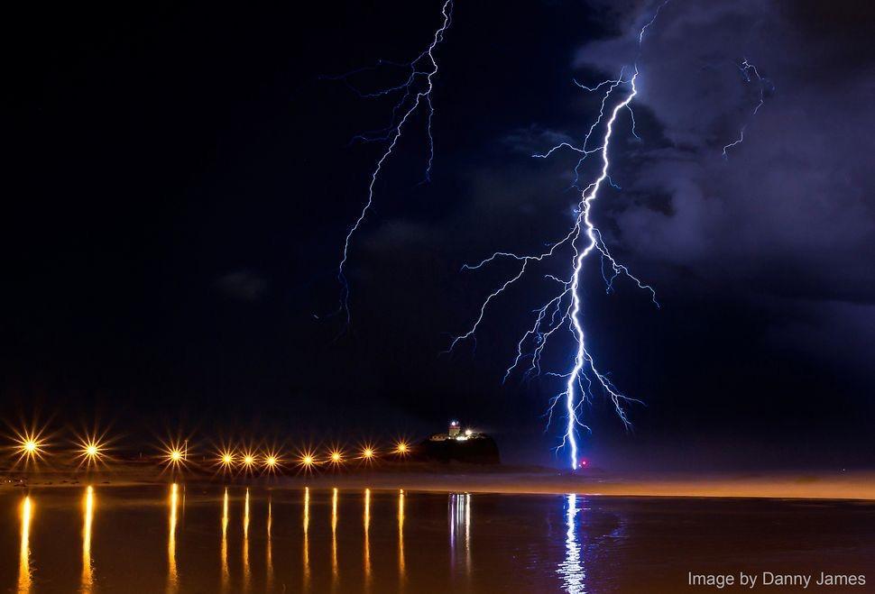 An amazing photo of a lightning bolt streaking down to the beach near Nobby’s Lighthouse | Scrolller