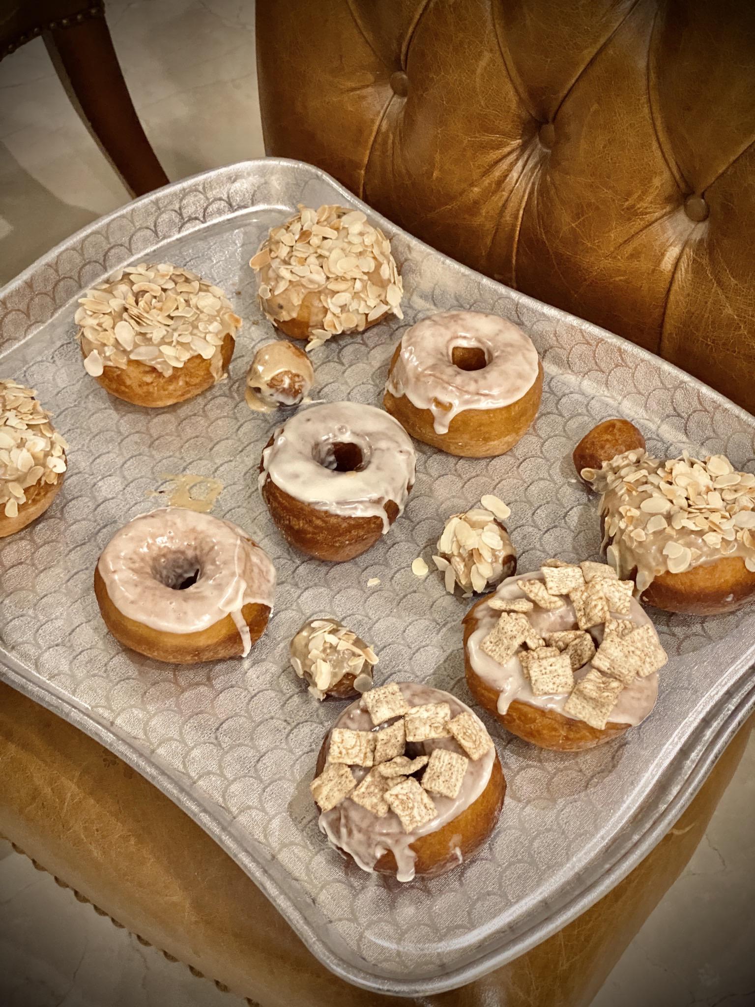 Fresh homemade raised donuts with coffee glaze and toasted almonds, cereal with milk glaze, and ...