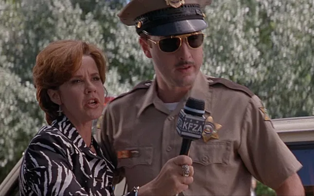 In Scream (1996), Linda Blair plays a reporter that harasses Sidney. She is also wearing ...