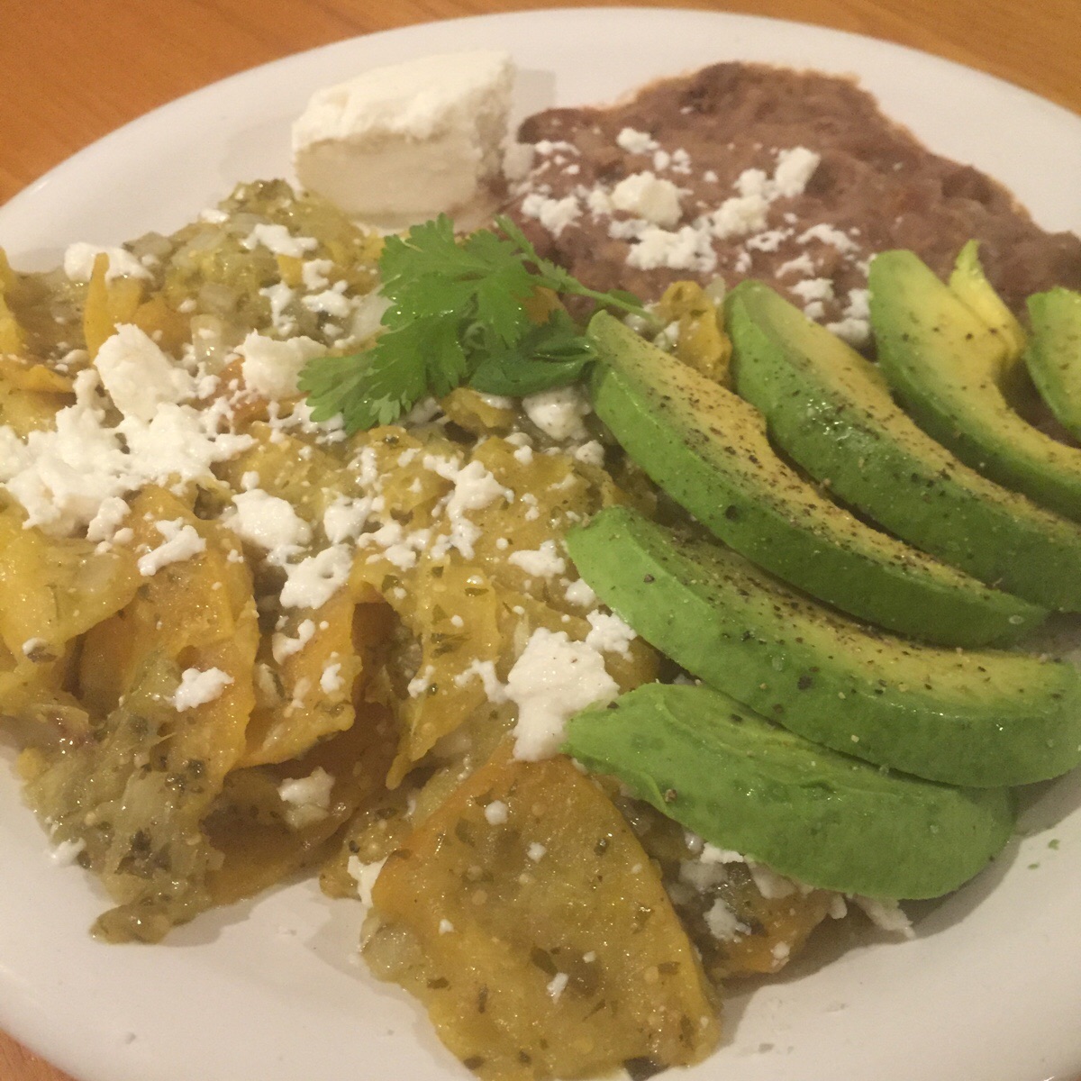 Late night munchies. Green chilaquiles with fried beans, avocado slices, and crumbled queso ...