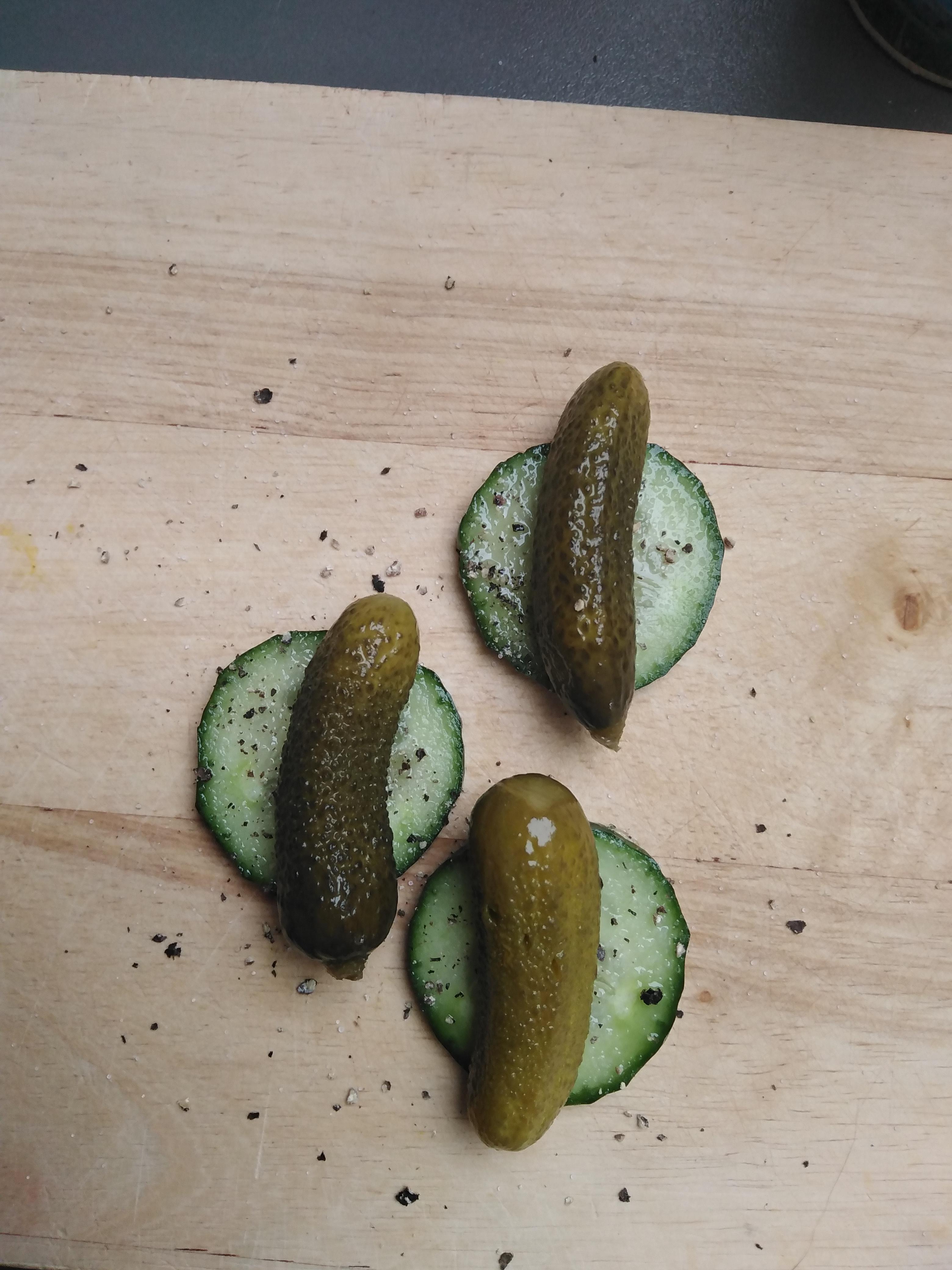 Pickles (7) on cucumber slices (3) served on a lightly spiced cutting board | Scrolller