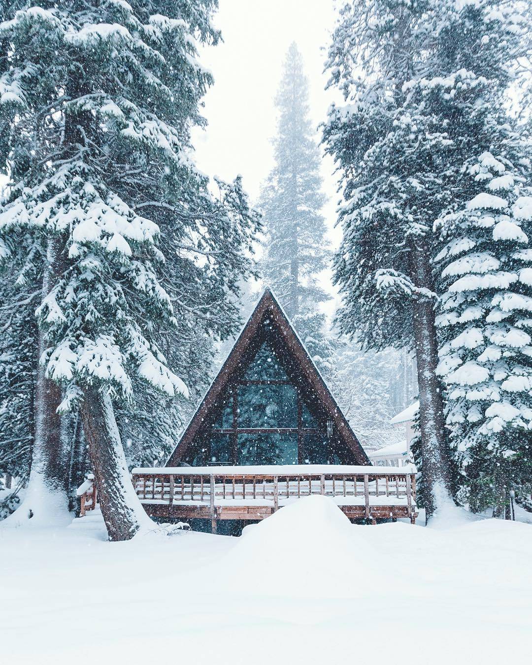 Snow falls on an A-frame cabin in the woods [1080x1350] | Scrolller