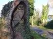 Owl sculpture nestled in an old tree trunk alive with Ivy | Scrolller