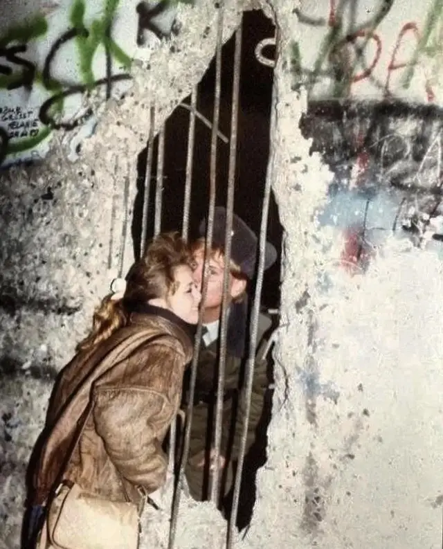 A woman and a NVA soldier kiss through a broken portion of the Berlin Wall (1989) | Scrolller