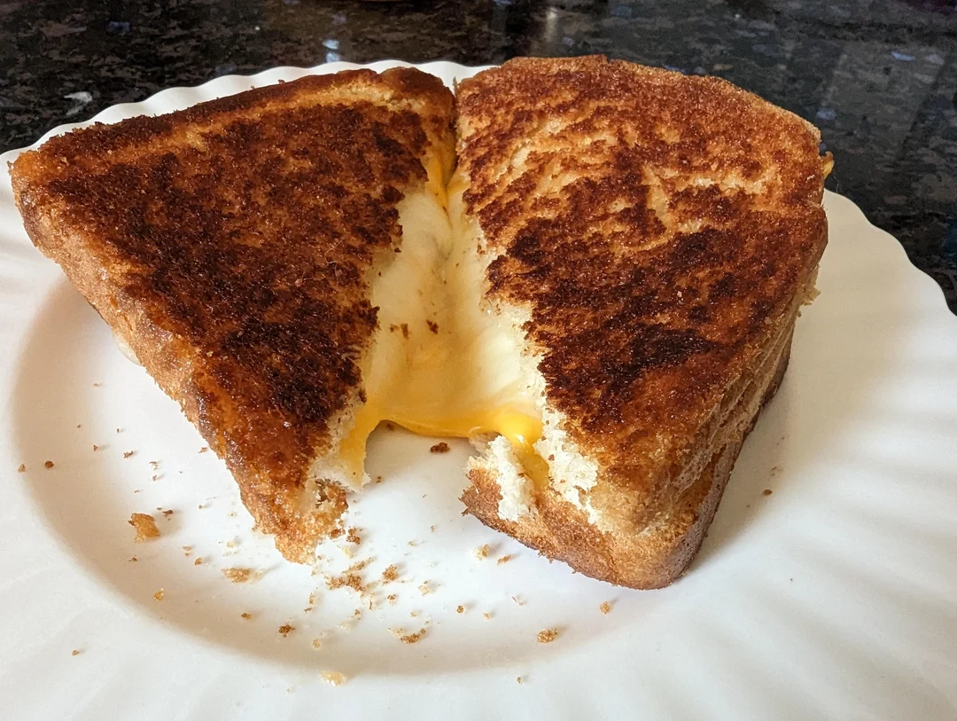 Kraft thick single plus shredded mozzarella on white bread with butter. | Scrolller