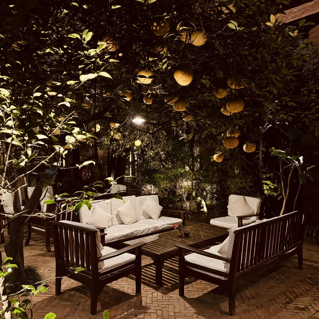 Patio seating under a canopy bearing large fruits (Dwarika Hotel, Kathmandu) | Scrolller
