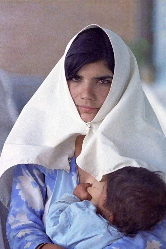 factory worker breastfeeding her child. Isfahan, iran, 1971. | Scrolller