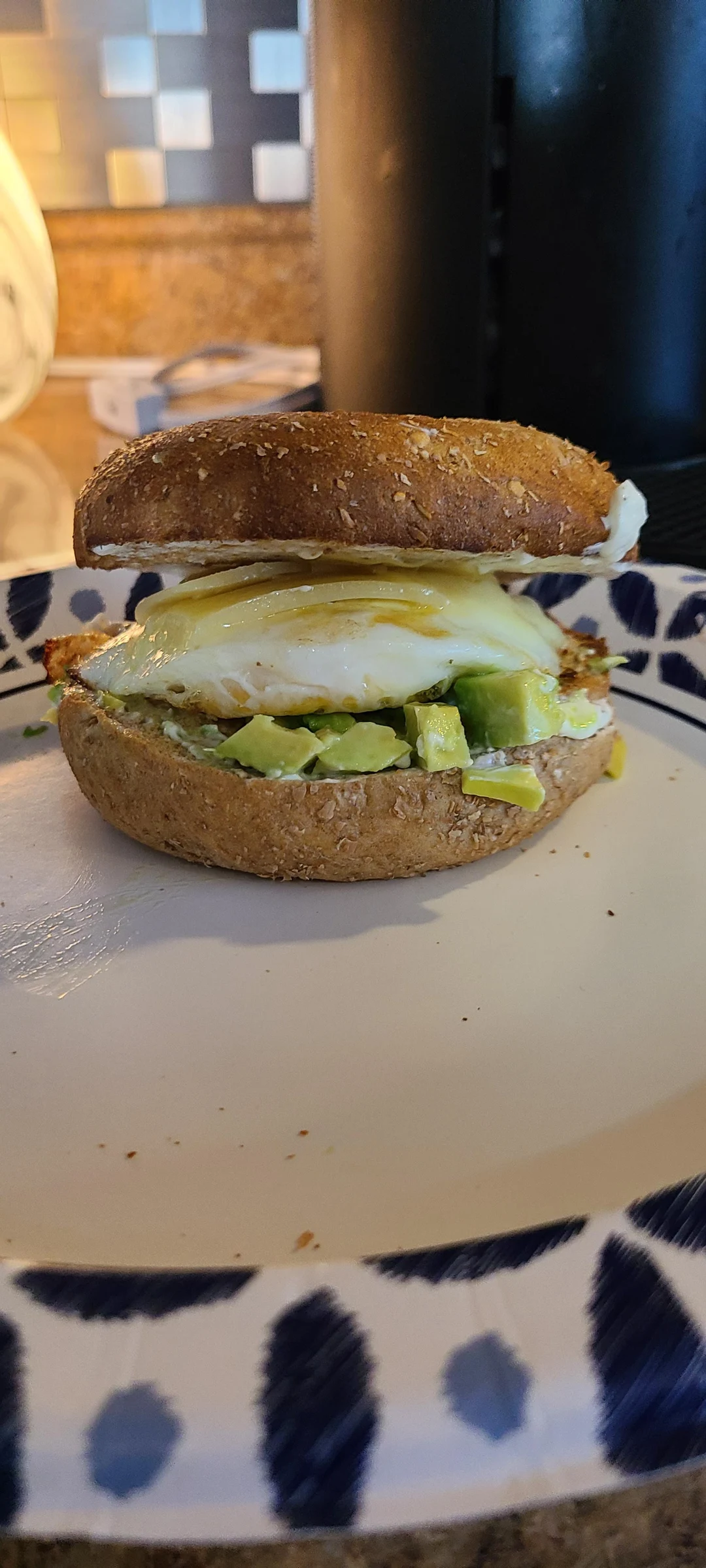 bagel and egg sandwich topped with avocado, cream cheese and gruyere cheese | Scrolller