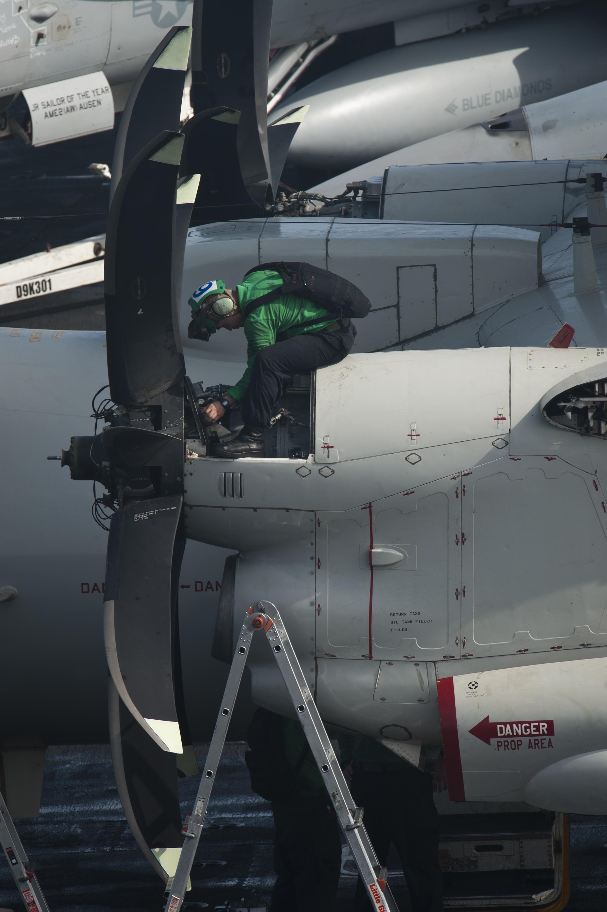 A U.S. Navy Sailor performs maintenance on an E-2C Hawkeye aircraft ...
