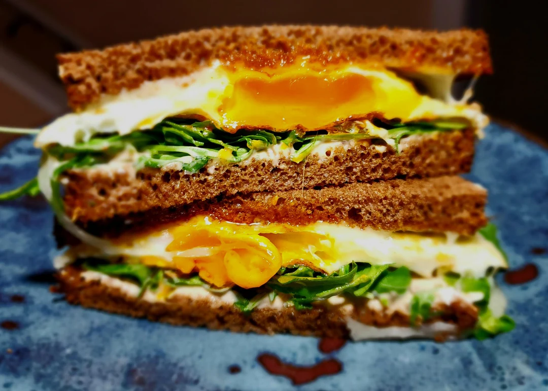 Fried egg, melted havarti, arugula, and sriracha mayo on toasted brown bread. | Scrolller