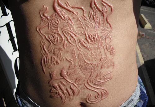 ‘Scarification’ - A form of body modification, involves scratching, etching, burning/branding or ...