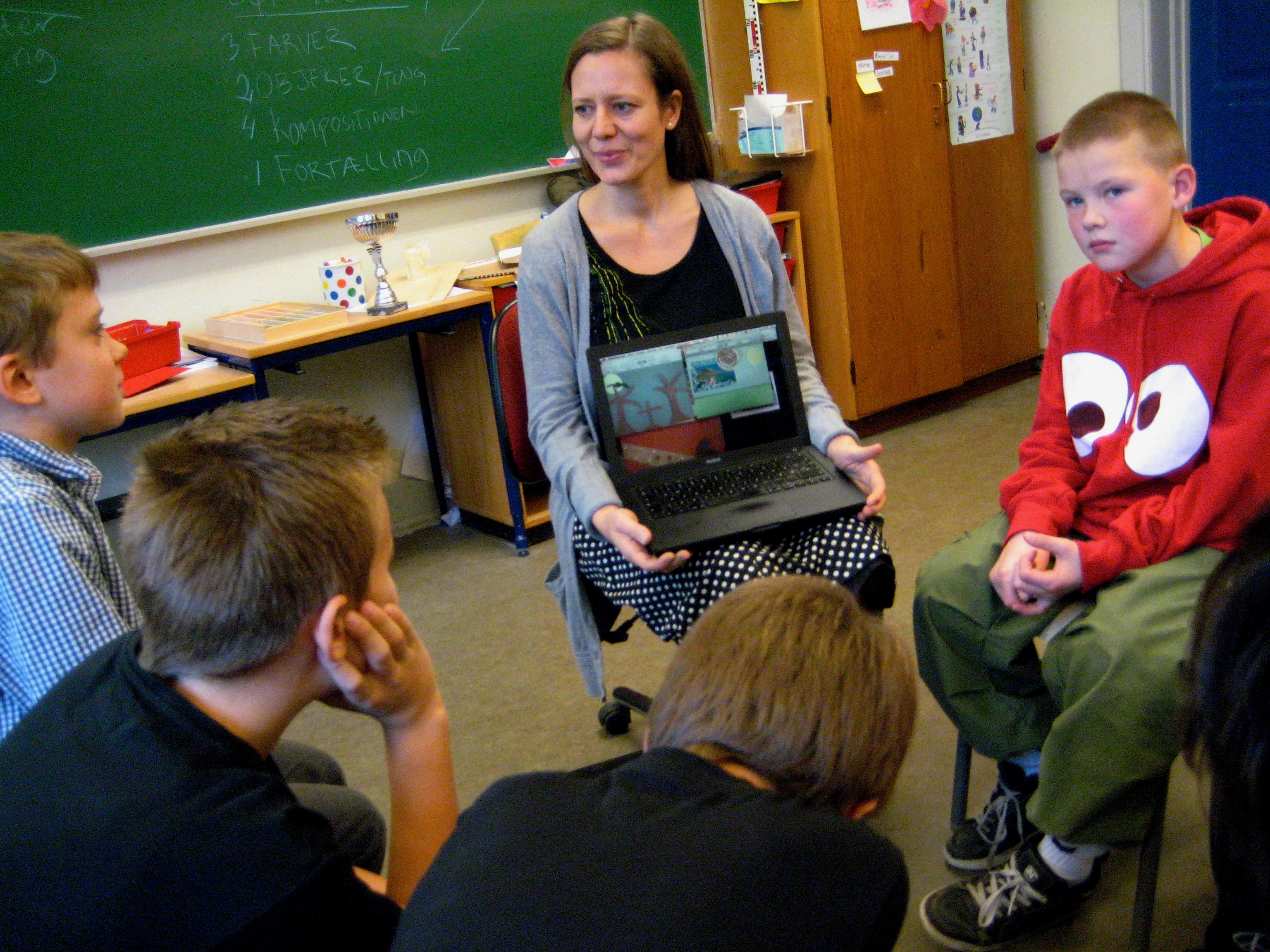 A teacher using laptop as part of a workshop for school children | Scrolller